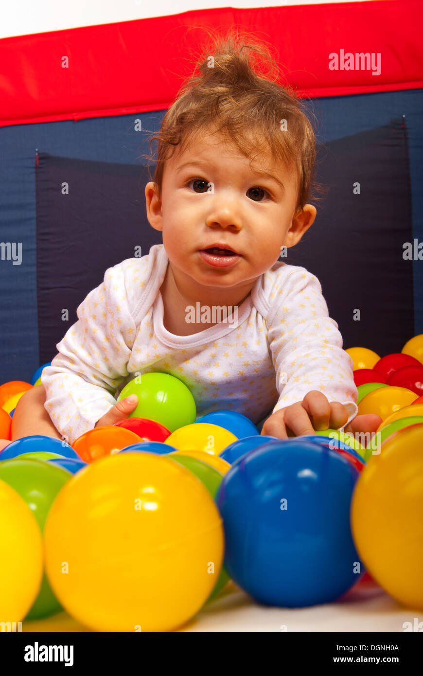 Baby boy playing with colorful balls inside playpen Stock Photo - Alamy