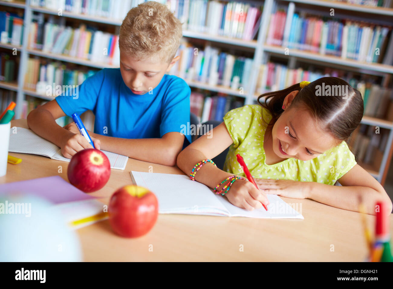Portrait of two schoolkids sitting in library and making notes Stock ...