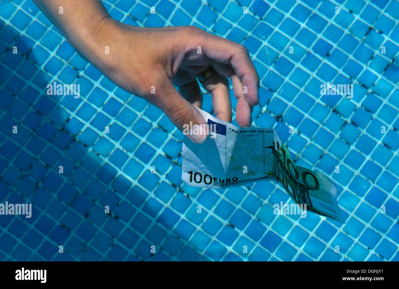Hand with euro note in a pool, symbolic image for the sinking of the ...