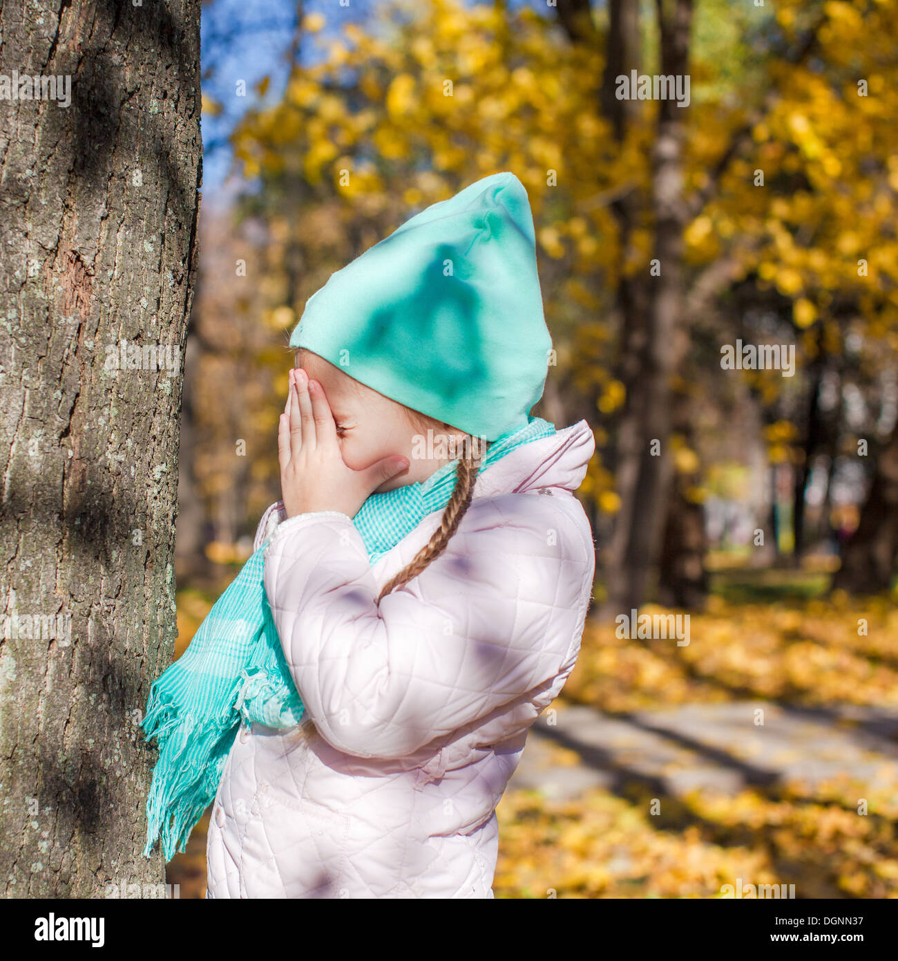 Little girl playing hide and seek in the autumn forest Stock Photo - Alamy