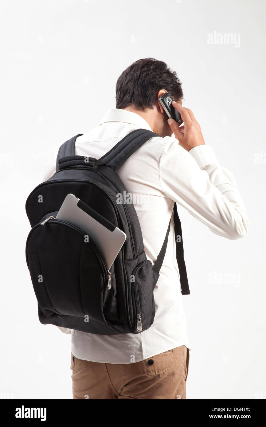 Man wearing a backpack, from which an iPad is sticking out, talking on ...