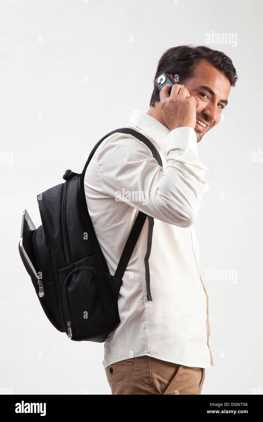Man wearing a backpack, from which an iPad is sticking out, talking on ...