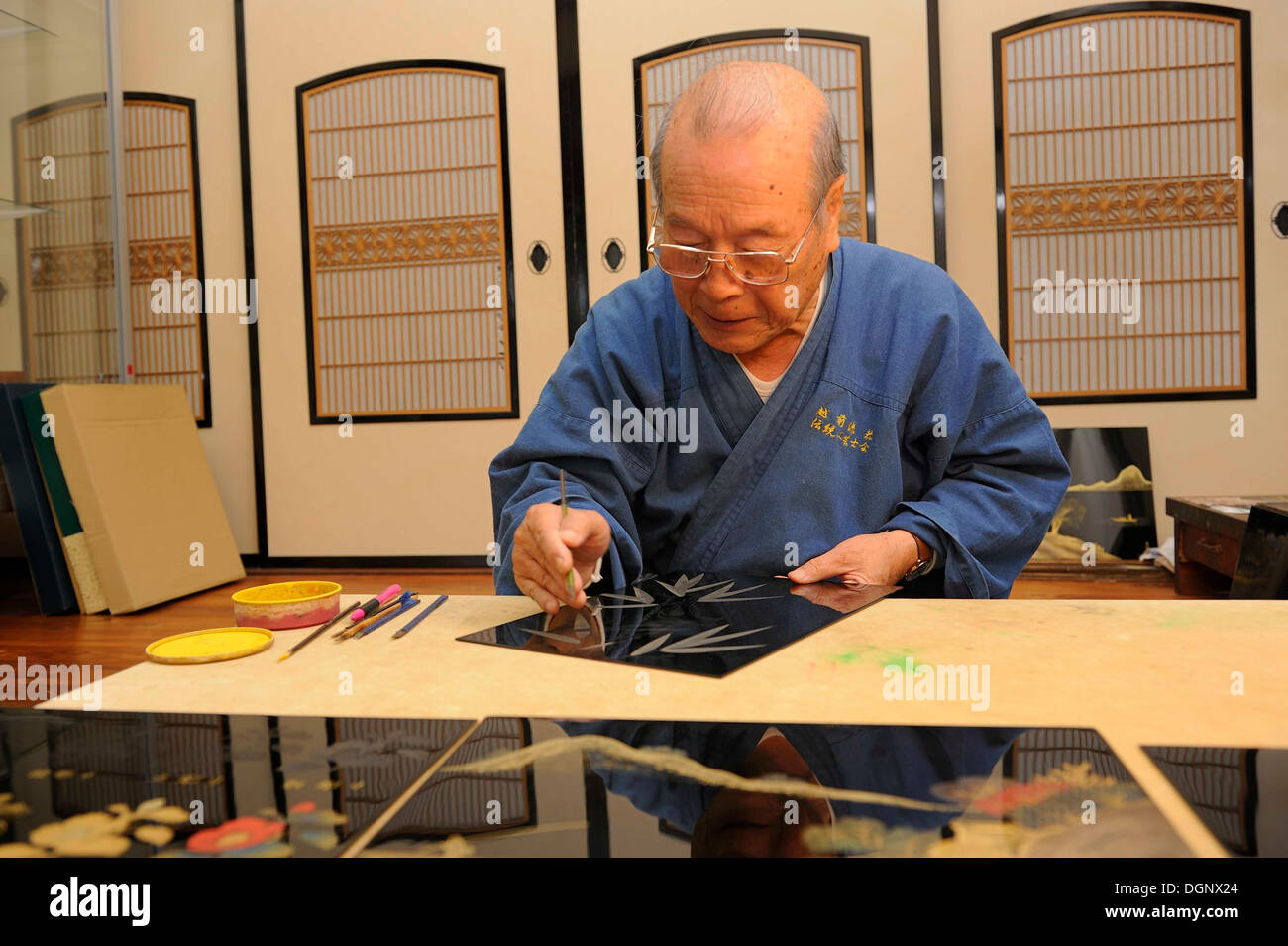 Japanese artisan in his workshop, scraping a bamboo motif into the top ...