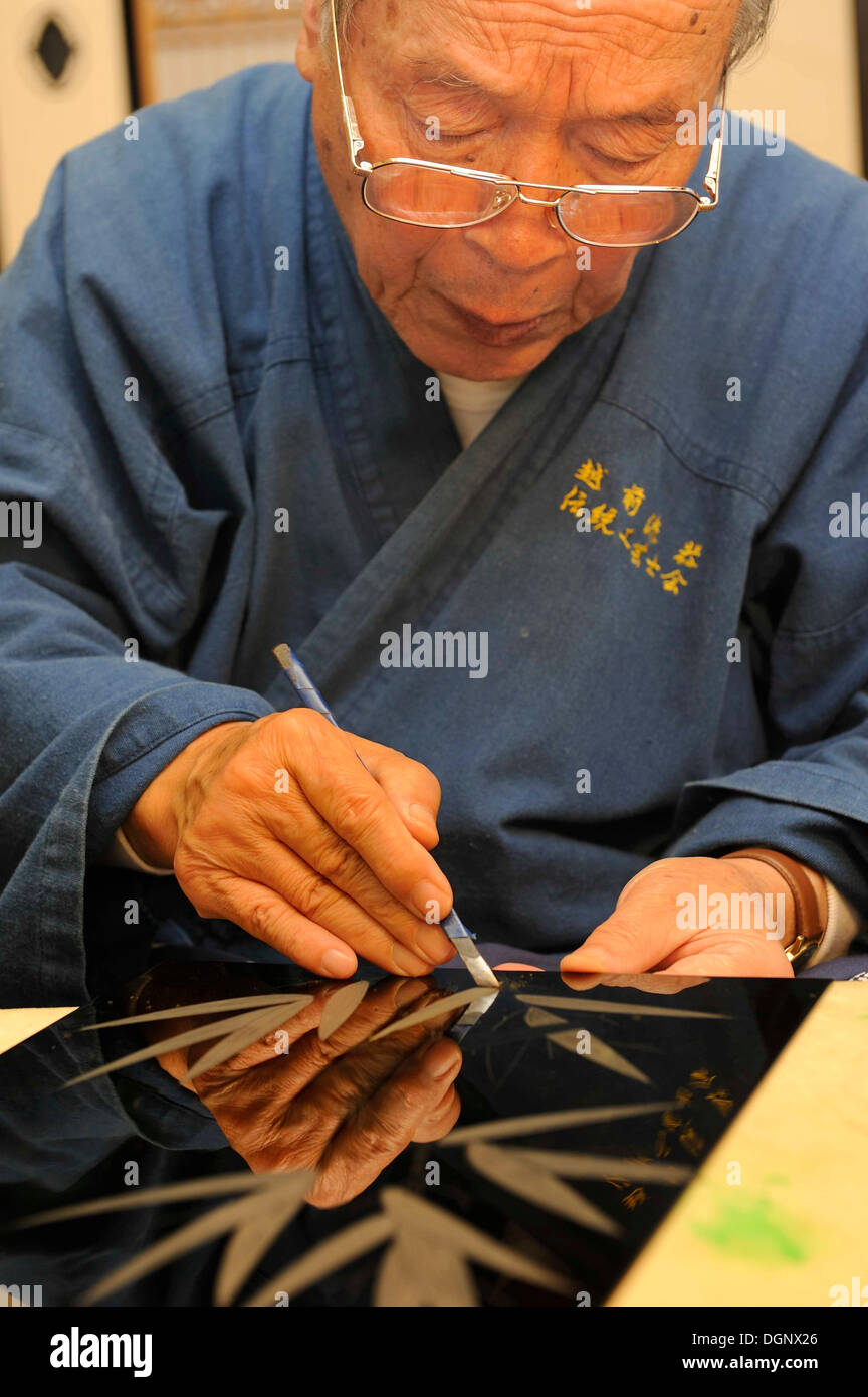 Japanese artisan scraping the top lacquer coat away to carve out golden ...