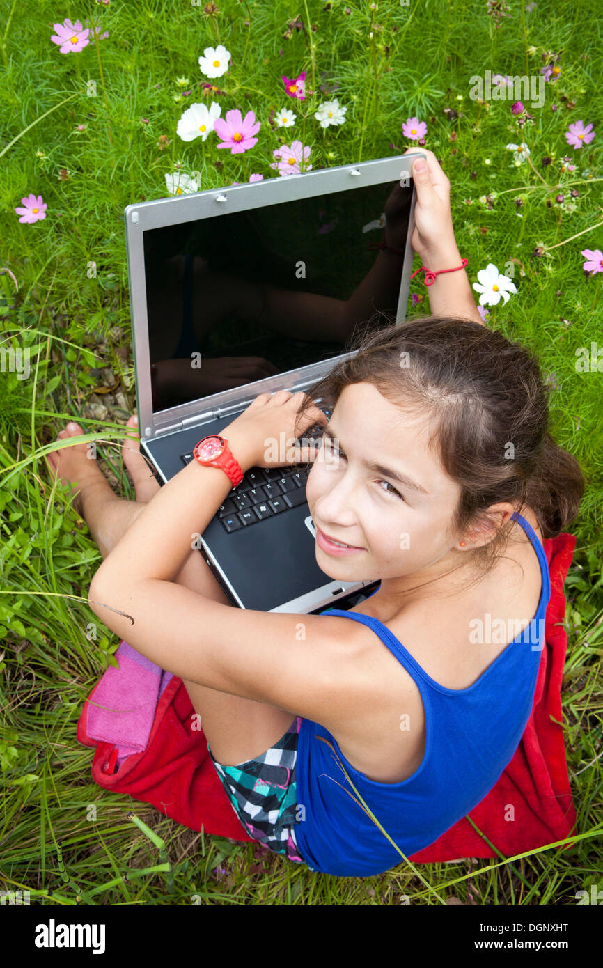 Girl, 11 years, sitting on a meadow with a laptop computer Stock Photo ...