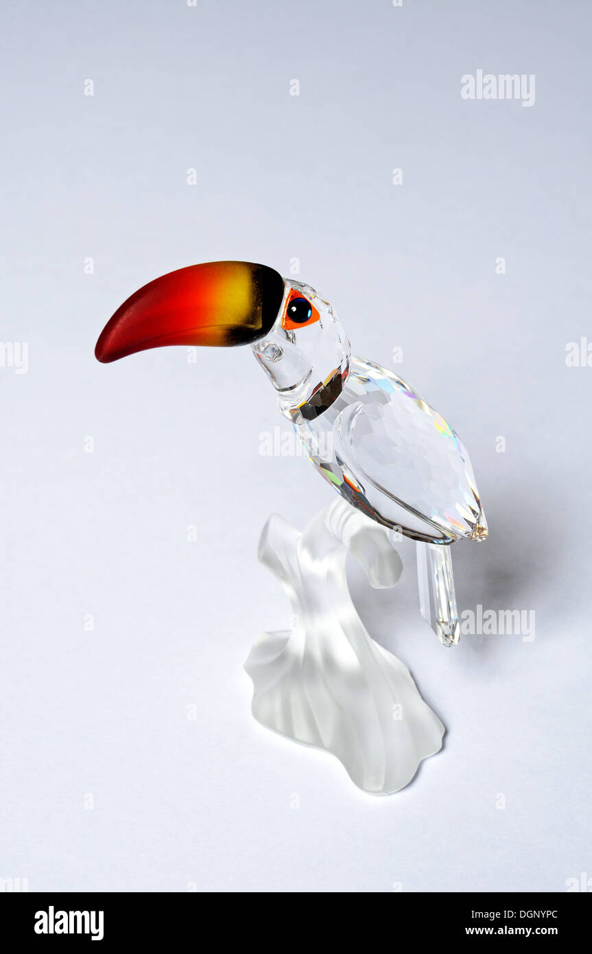 Glass crystal Toucan sitting on a branch against a plain background ...