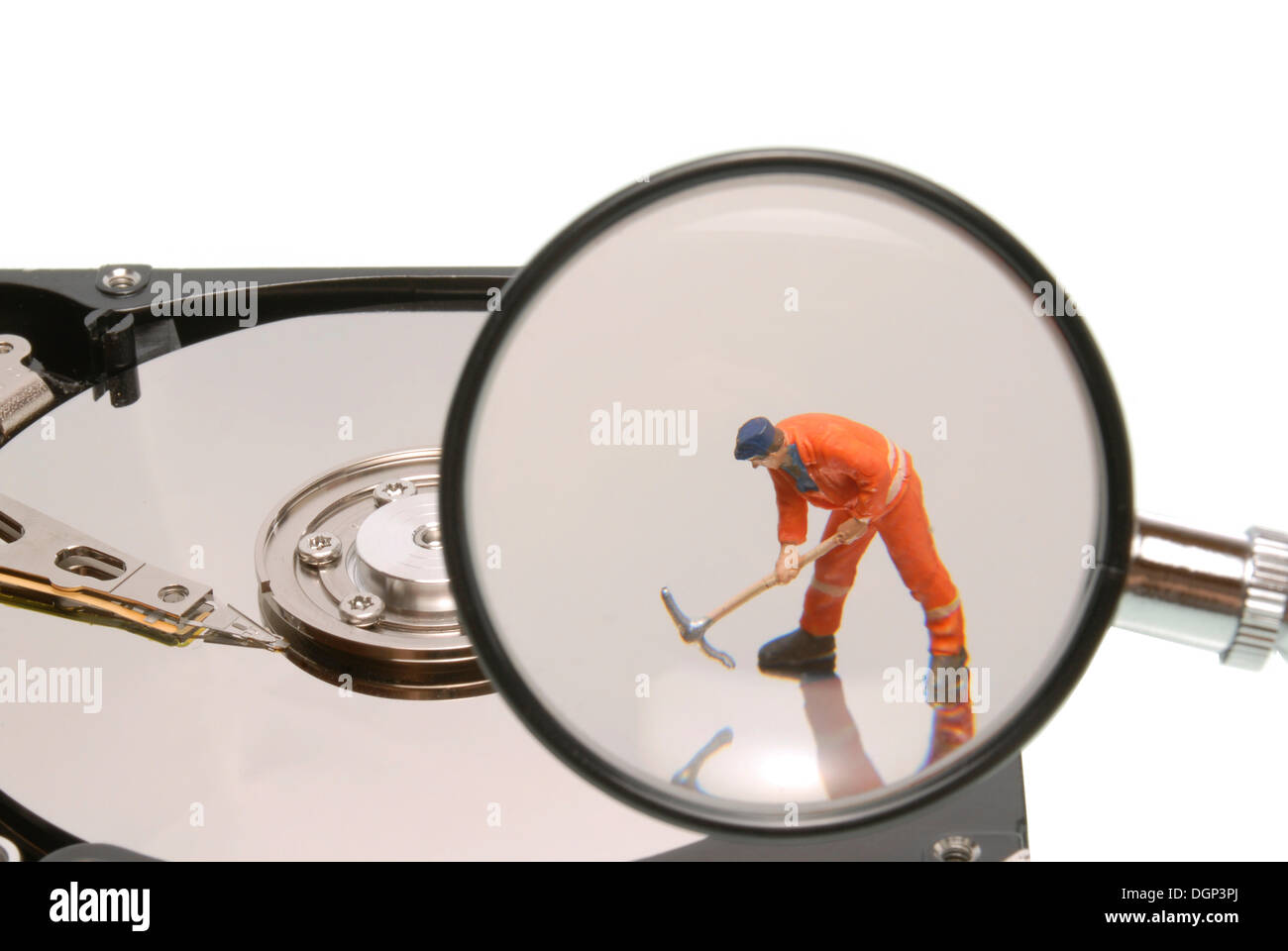 Small construction worker figure on a hard drive with magnifying glass ...