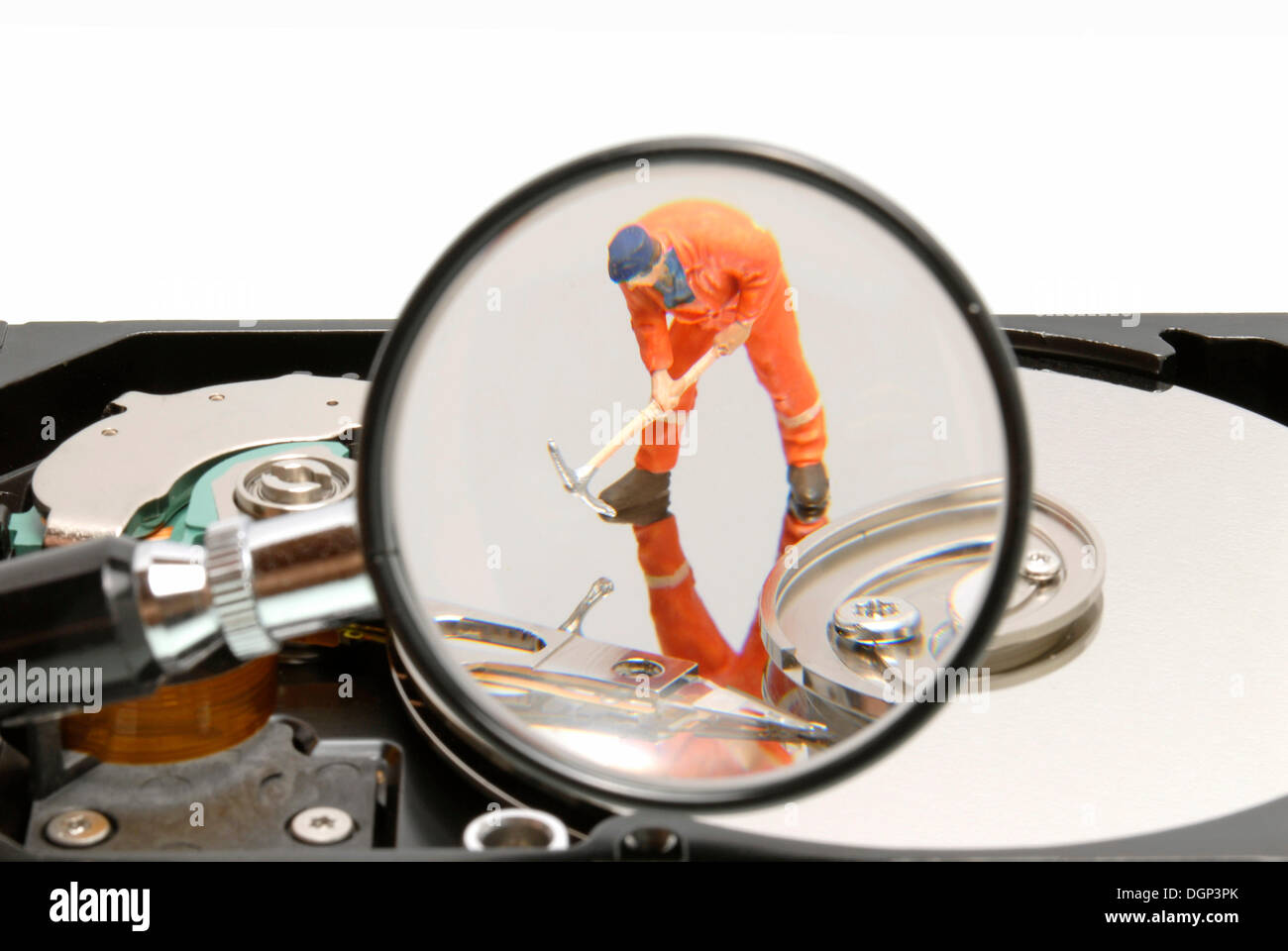 Small construction worker figure on a hard drive with magnifying glass ...