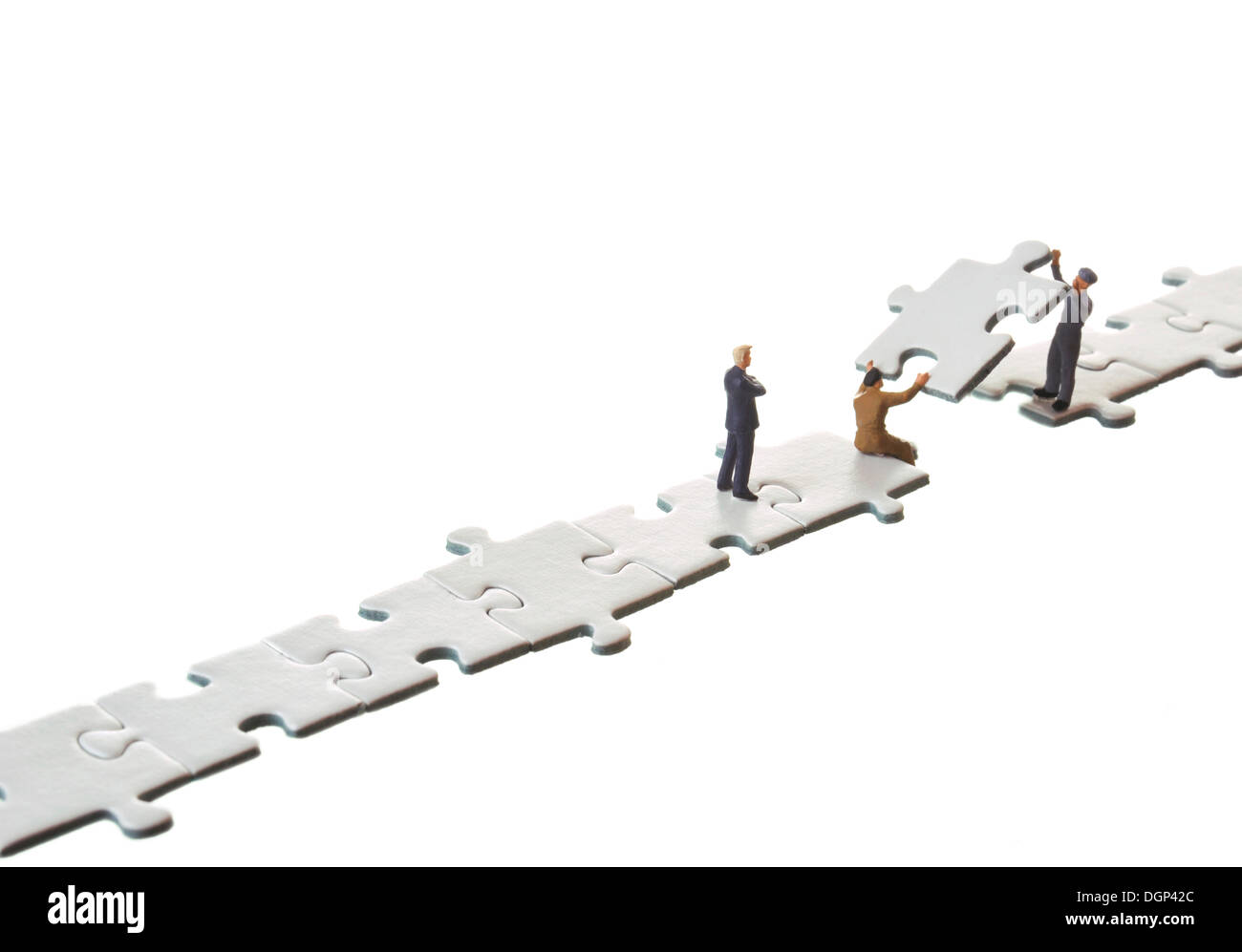 Figures of businessmen building a bridge with puzzle pieces, symbolic ...