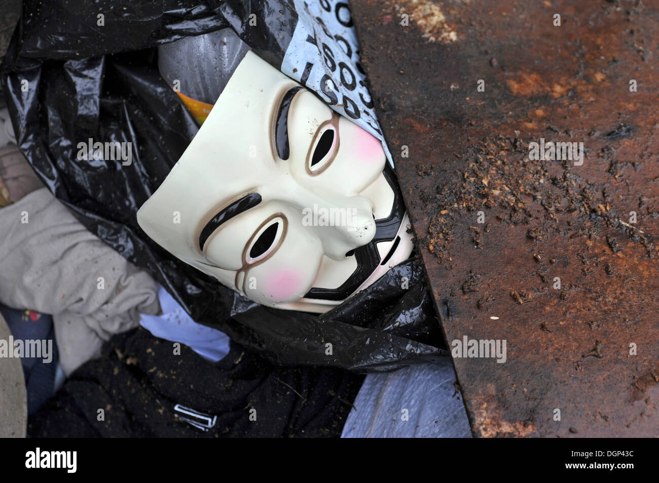 Anonymous mask, Guy Fawkes mask lying in a pile of garbage, symbolic ...