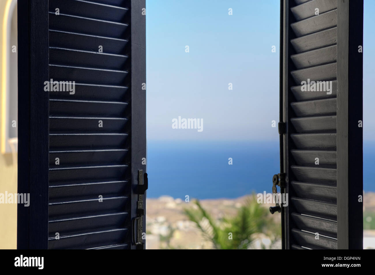 View on the ocean through the half open shutters of a hotel room, Fira ...