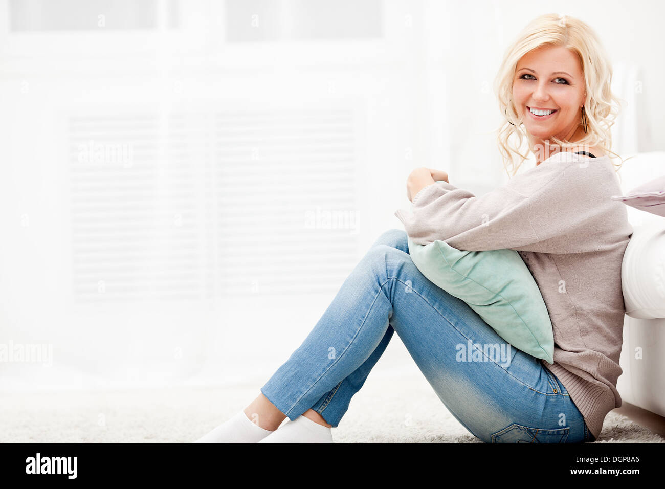Smiling girl sitting on carpet Stock Photo - Alamy