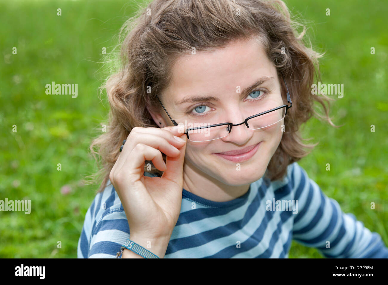 Young woman looking over the rim of her glasses, portrait Stock Photo ...