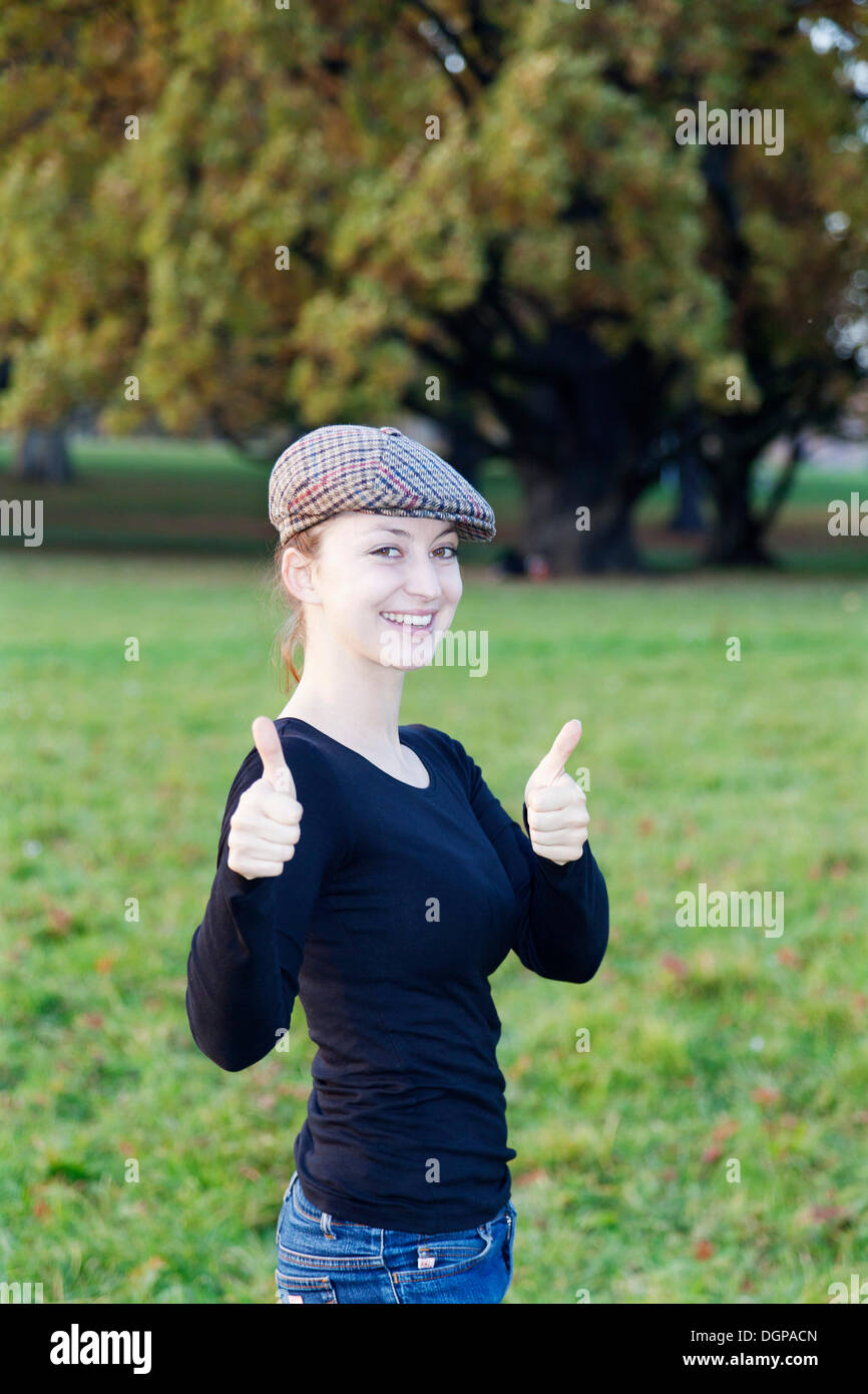 Young woman with cap, two thumbs up Stock Photo - Alamy