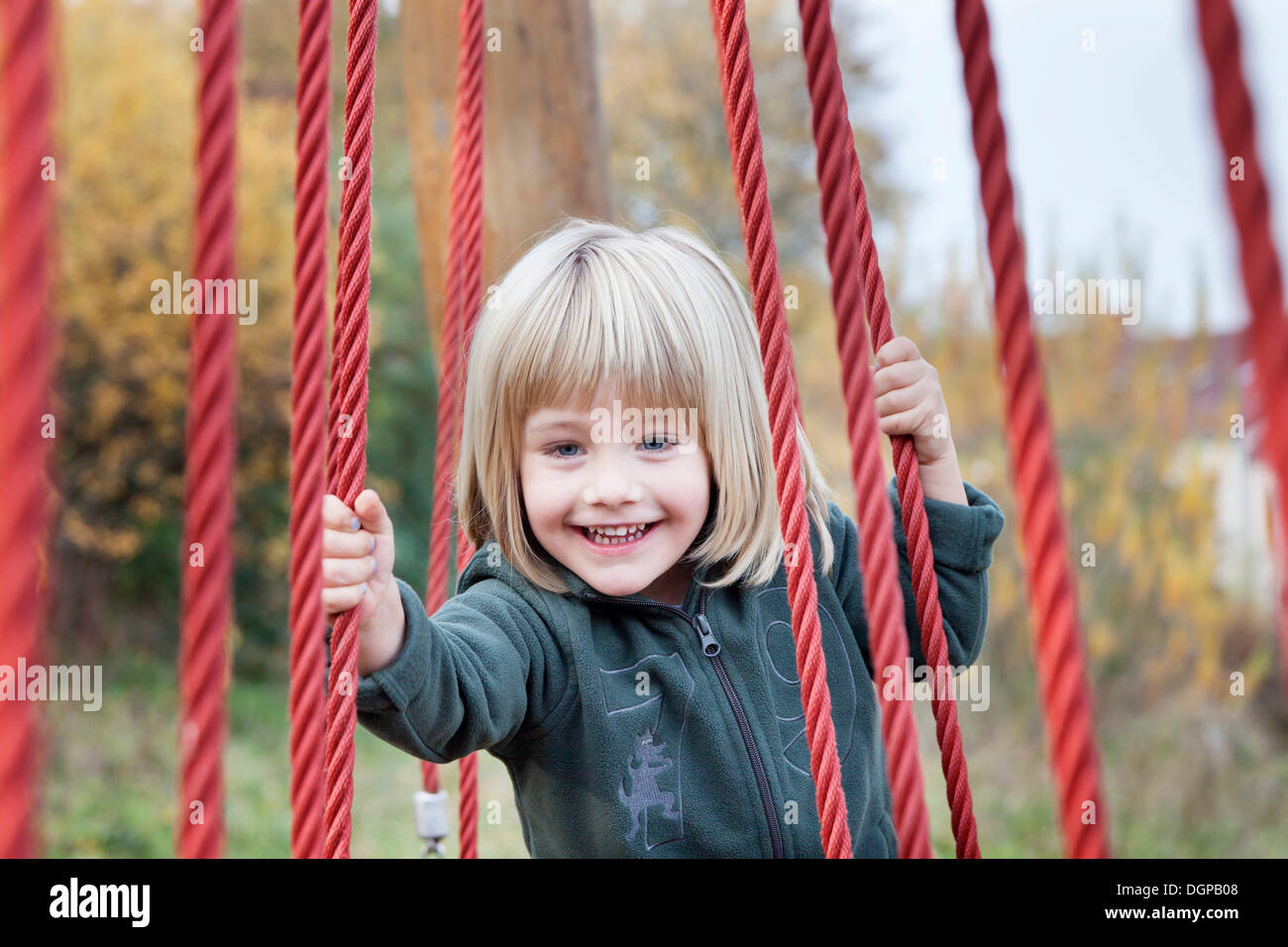 Boy, 4 years, holding onto ropes whilst balancing, children's ...