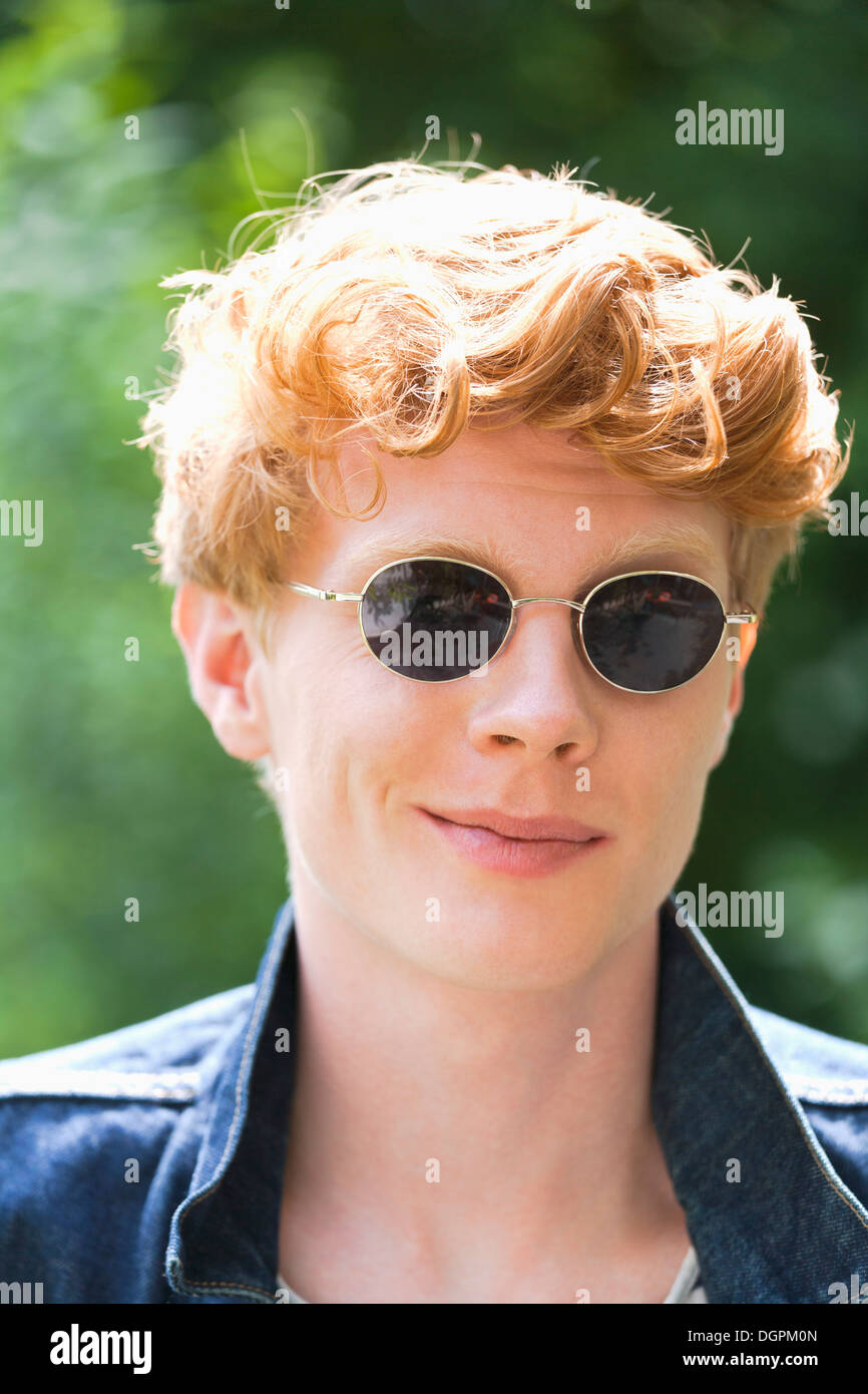 Germany, Bavaria, Munich, Young man with sunglasses, smiling, close up ...