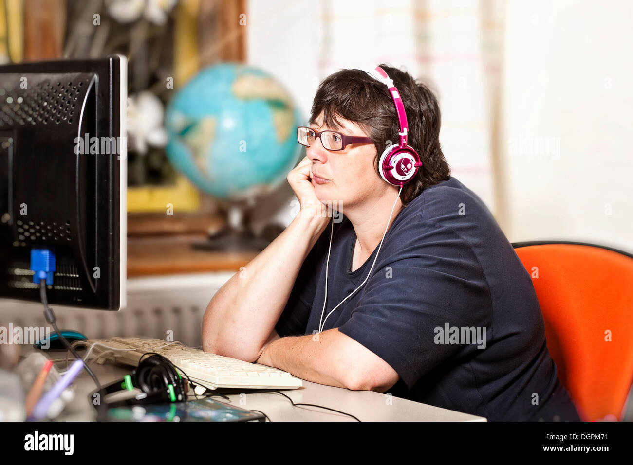 Woman wearing headphones sitting boredly in front of a computer Stock ...