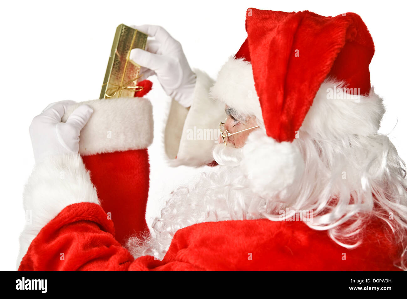 Santa Clause putting a shiny Christmas present into a stocking ...