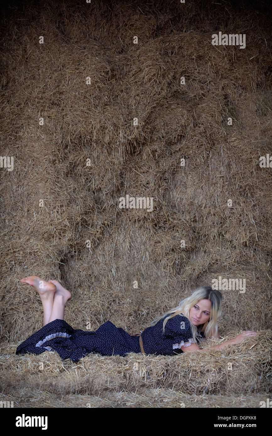 a blond woman is lying in the hay Stock Photo - Alamy