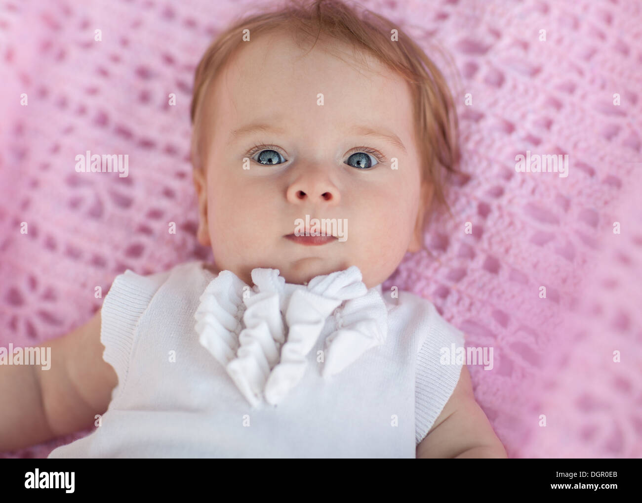 Sweet little baby girl lying on her back wearing a white jacket ...
