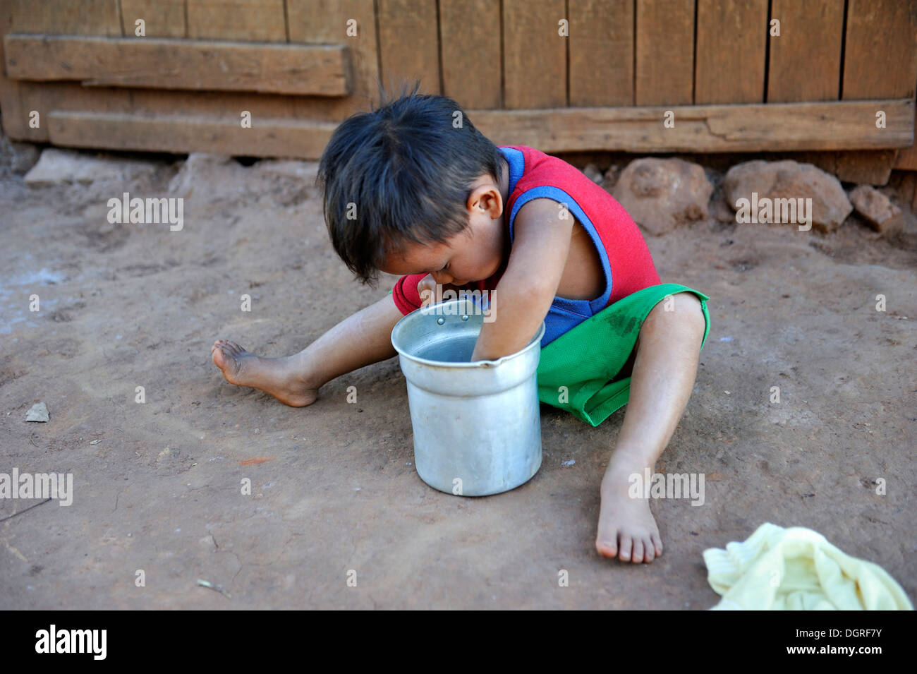 Paraguay, Caaguazu, Jaguary, Guarani boy looking for food rests in pot ...