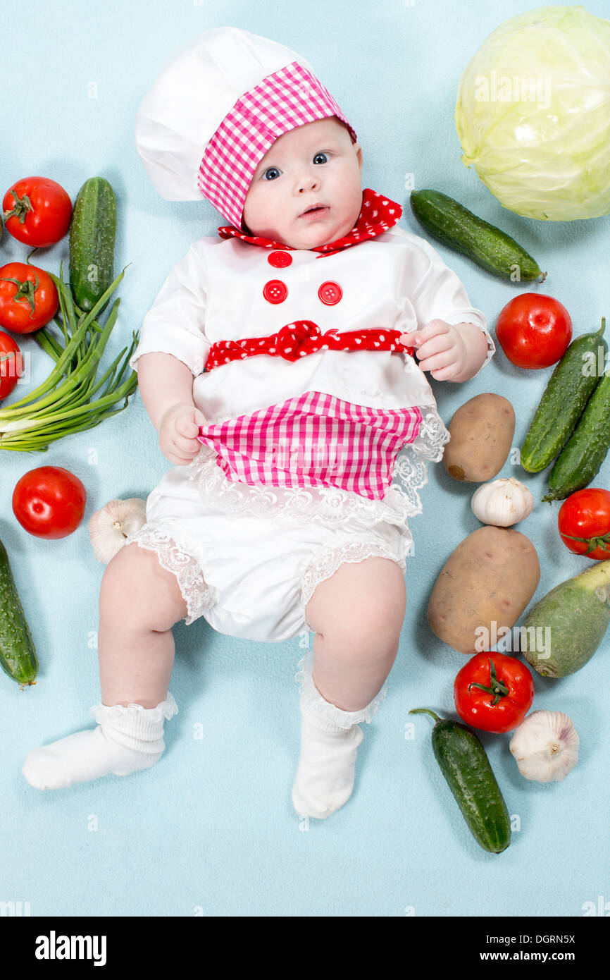 Baby cook girl wearing chef hat with fresh vegetables. Use it for a ...