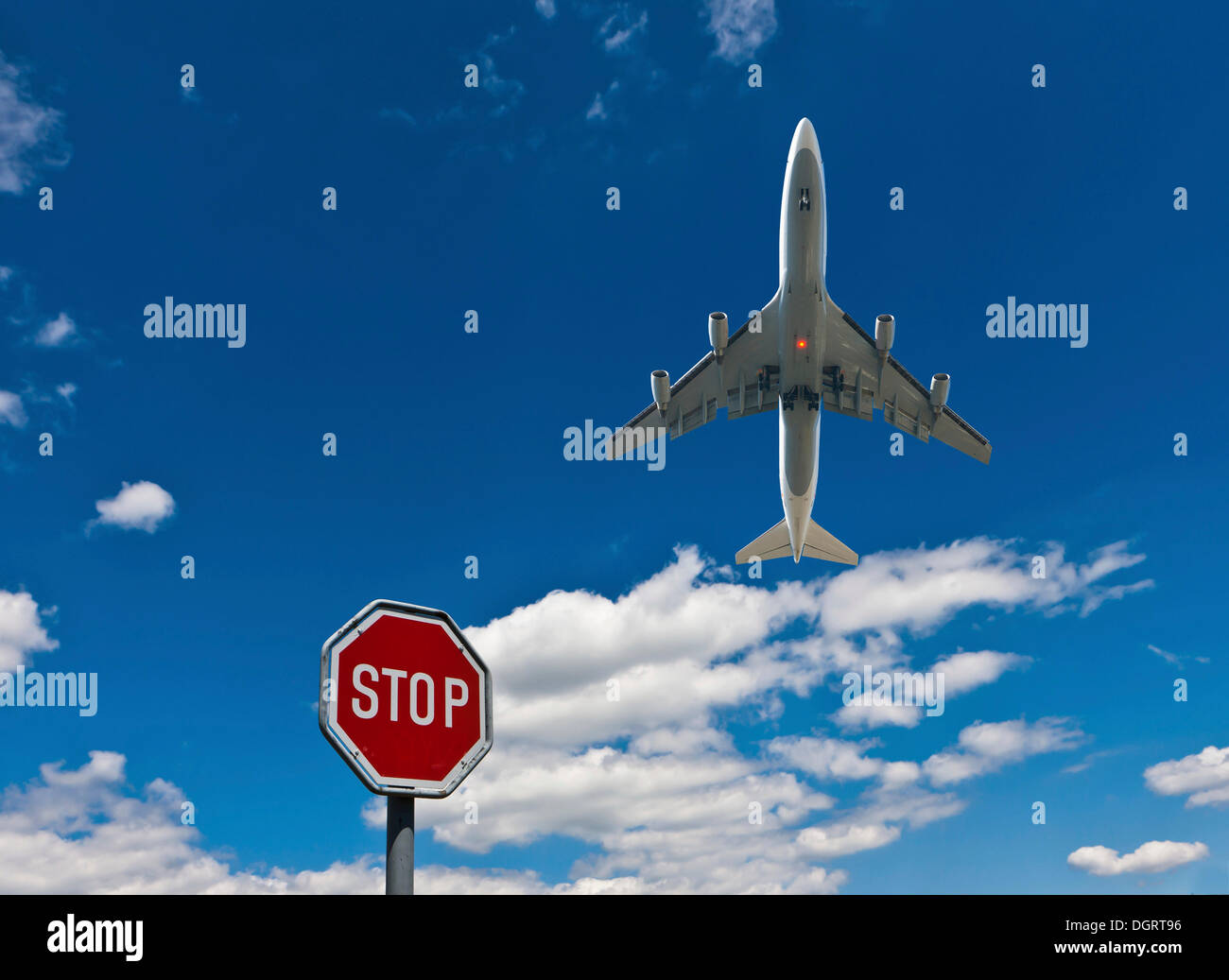 Stop sign against a blue sky with clouds and an aircraft, symbolic ...