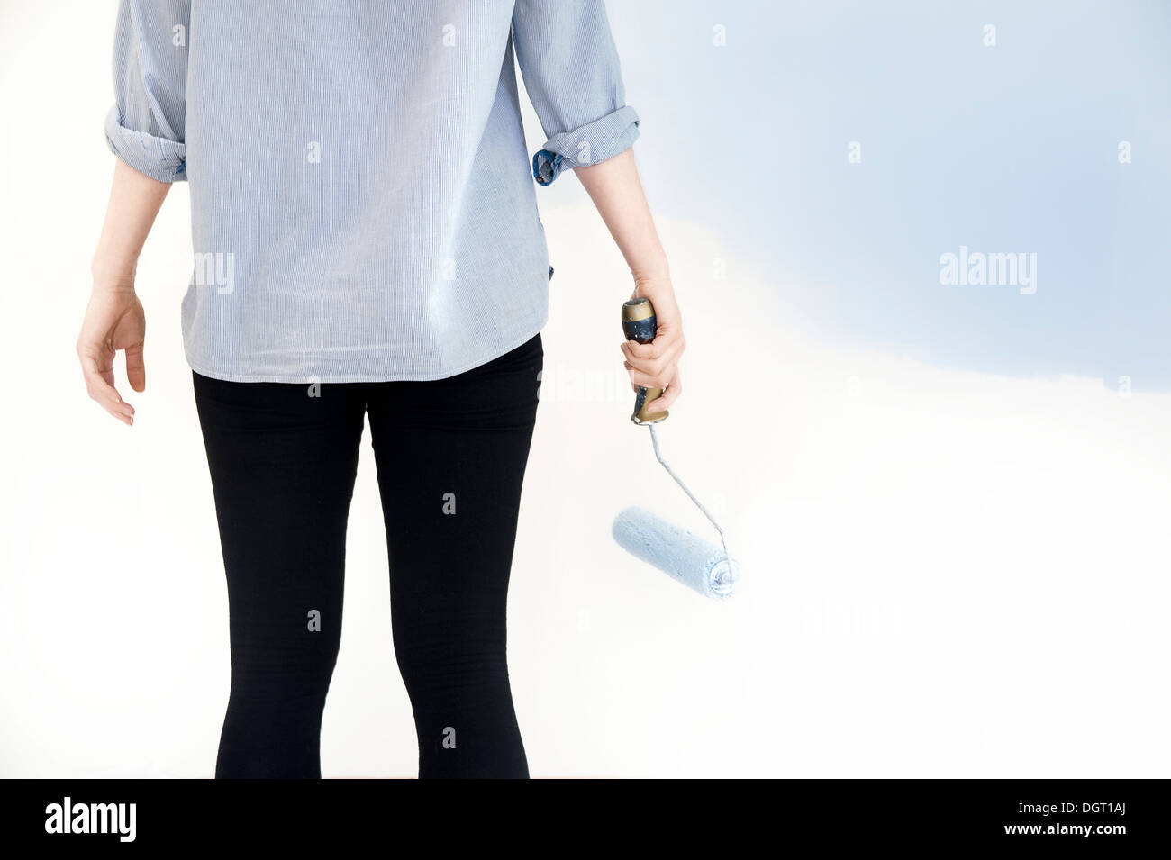 Young woman painting wall with paint roller Stock Photo - Alamy