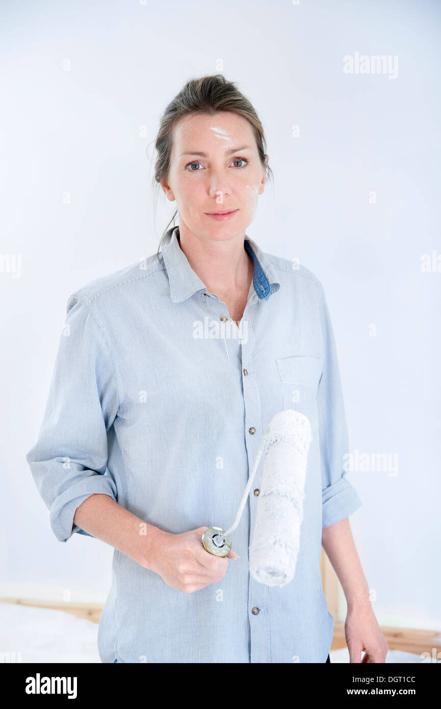 Young woman painting wall with paint roller Stock Photo - Alamy