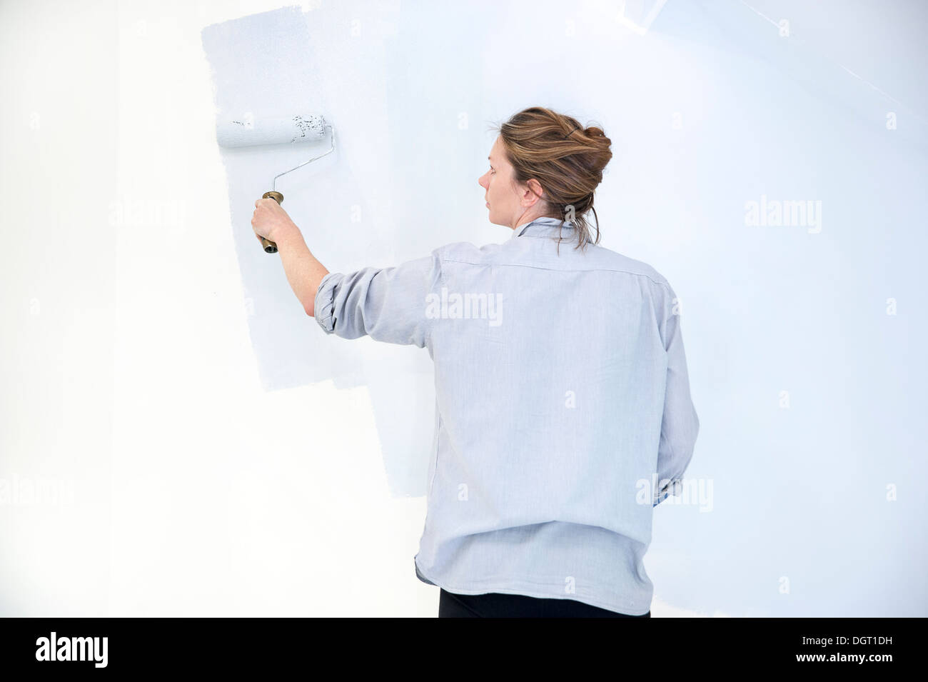 Young woman painting wall with paint roller Stock Photo - Alamy