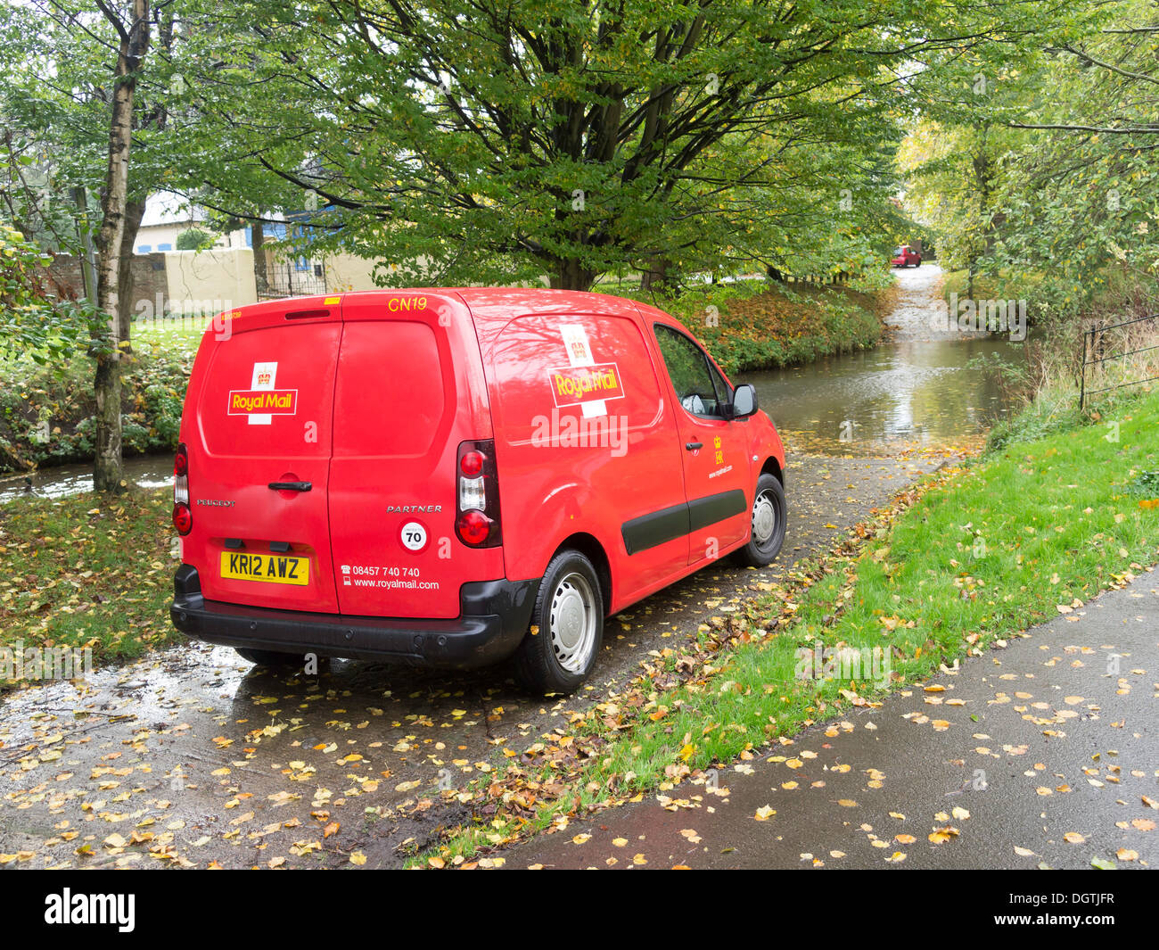 Smart clean bright red Royal Mail post van parked by a ford on a small ...