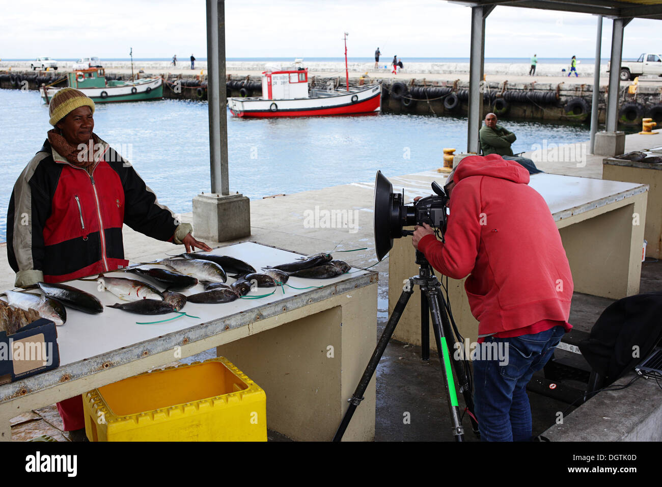 Fisherman selling his days catch while photographer photographs him ...