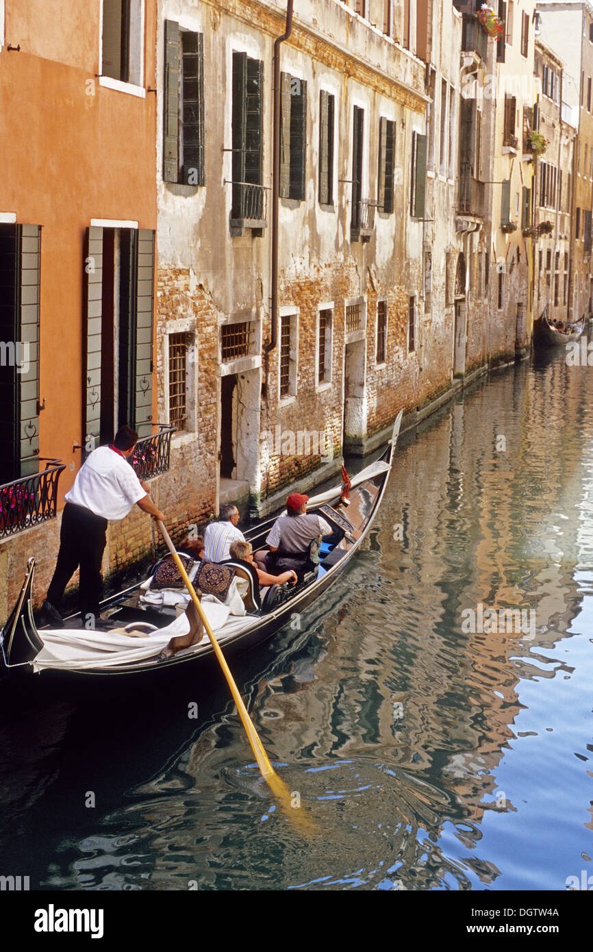 A gondolier steers his boat with passengers on a canal in Venice Stock ...