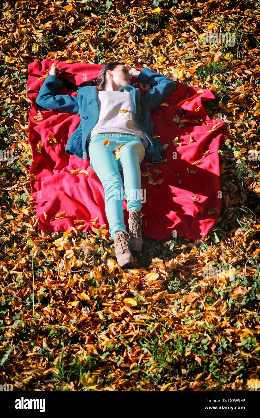 Fall lifestyle concept. Casual young woman girl relaxing on red blanket ...