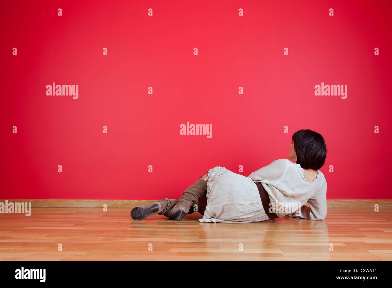 Woman sitting on the floor looking up to a red wall Stock Photo - Alamy