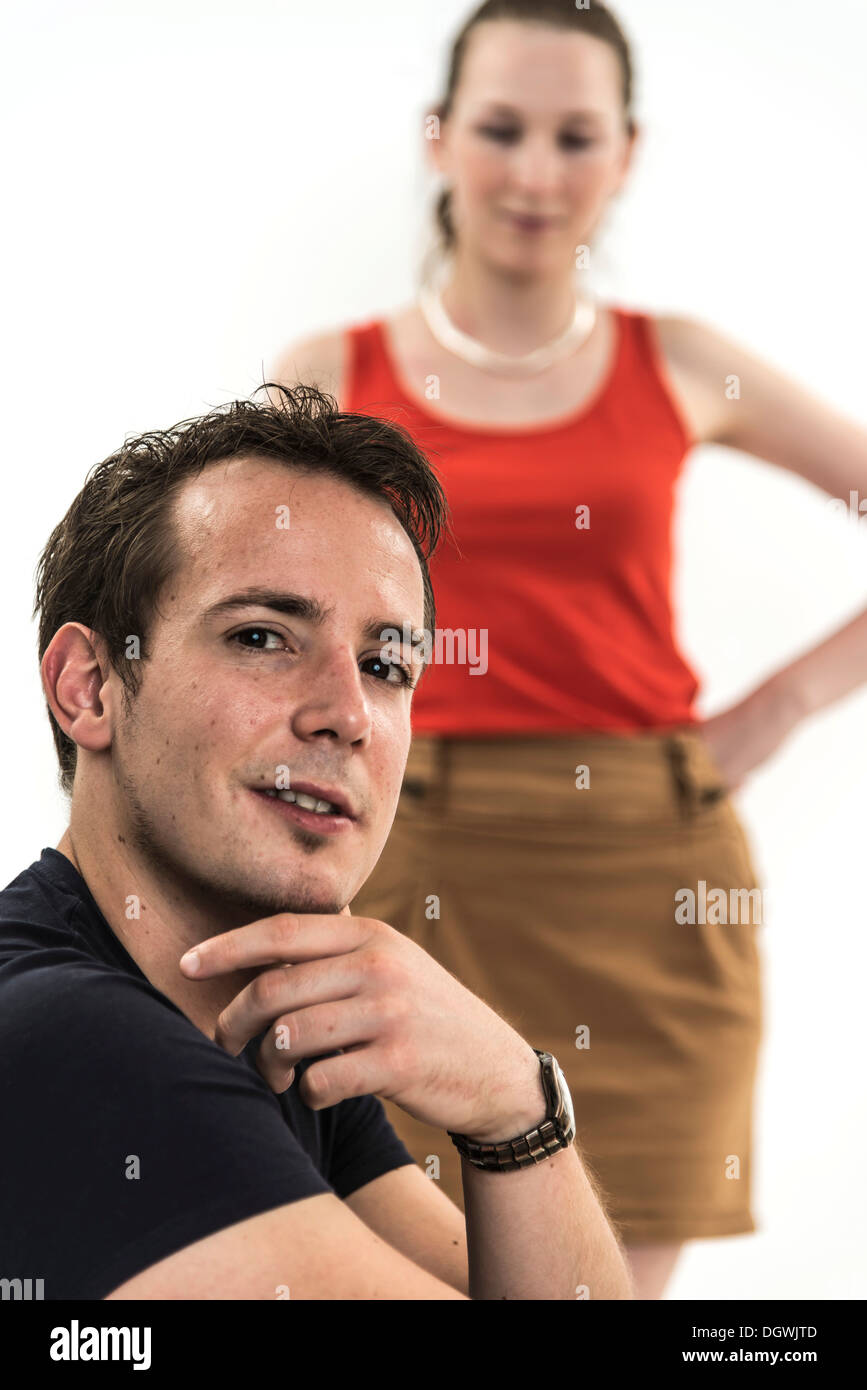 Man thinking, out of focus behind him stands a beautiful woman ...