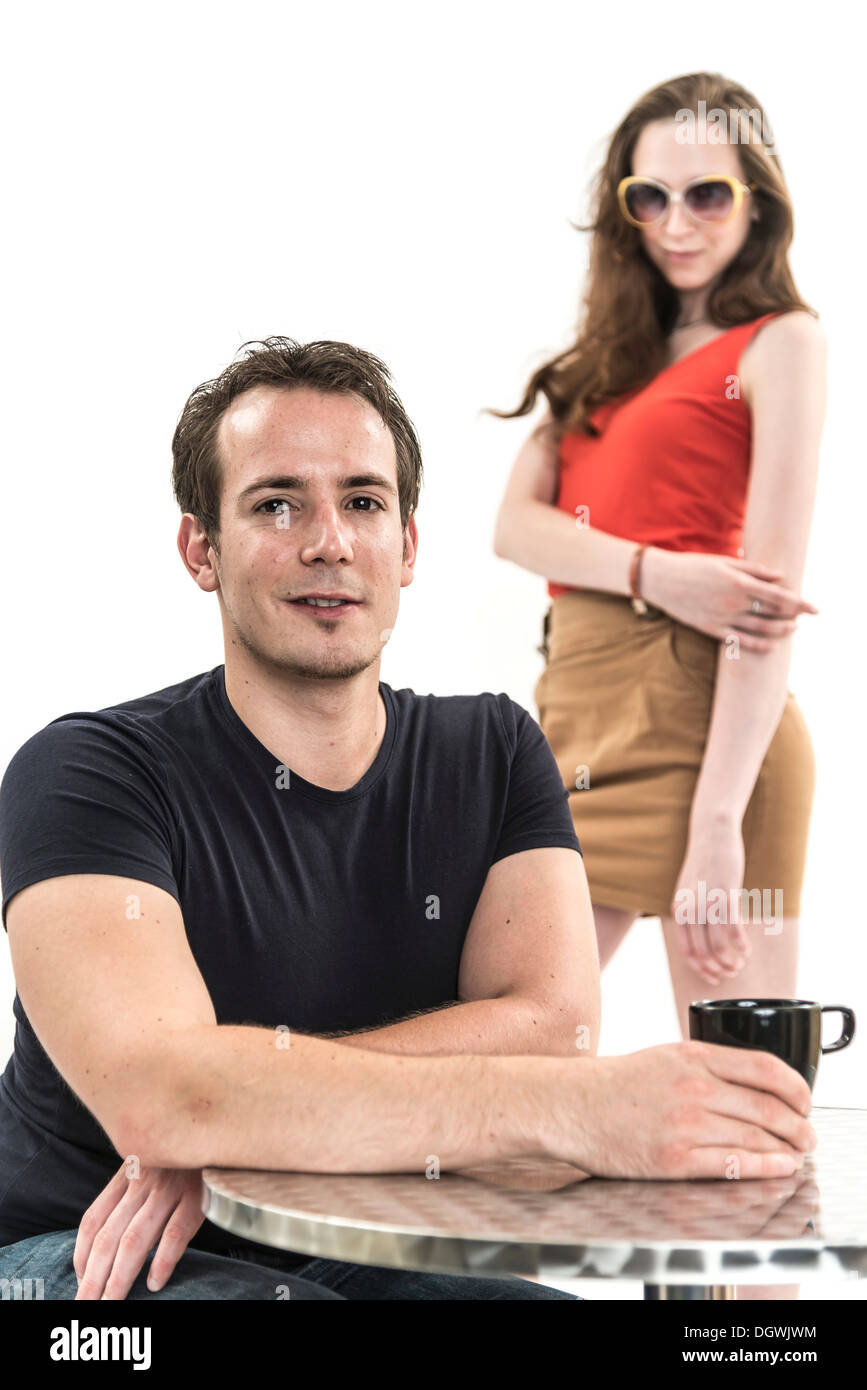 Man thinking, out of focus behind him stands a beautiful woman ...