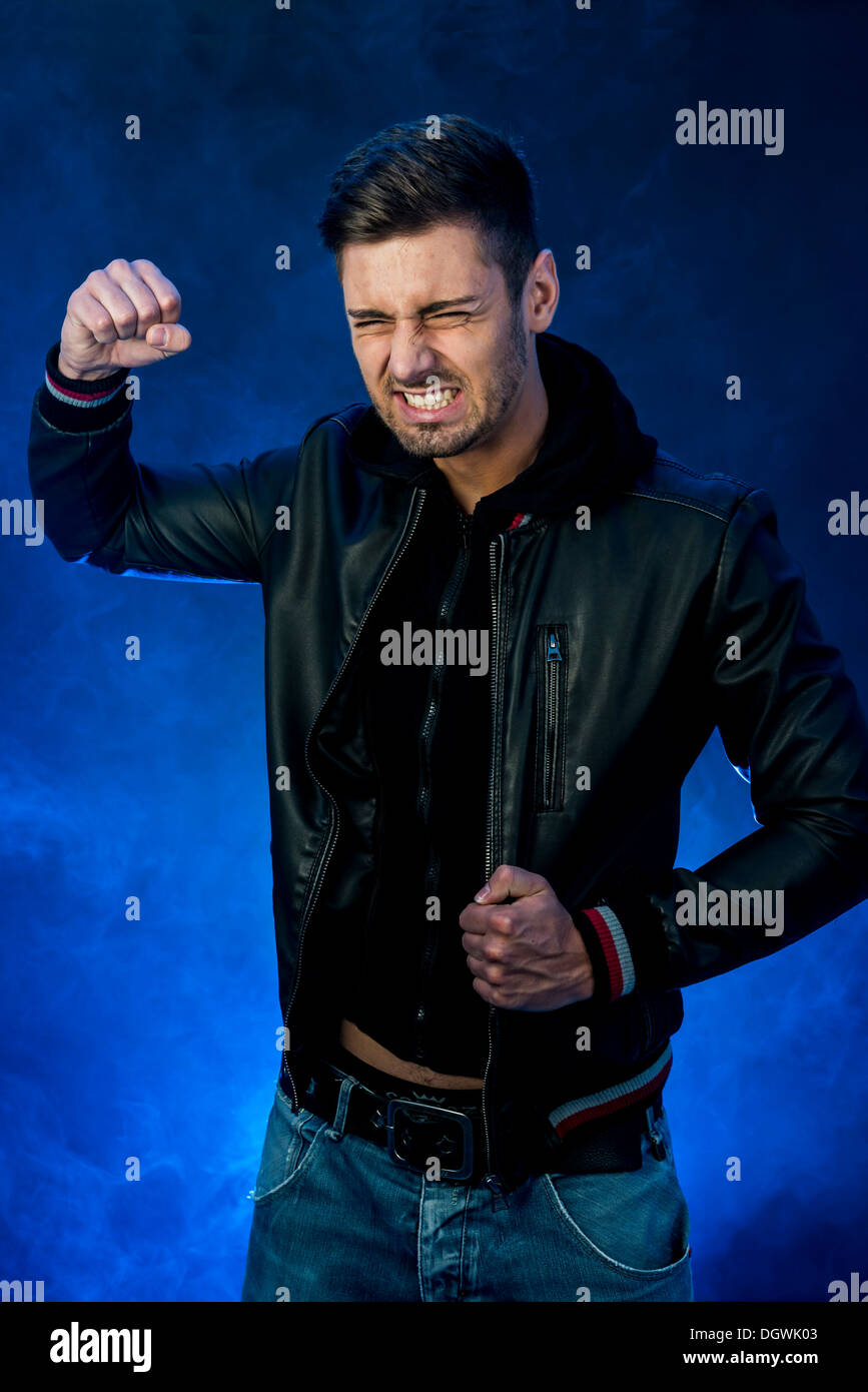 Young man wearing a black leather jacket, with an aggressive or angry ...