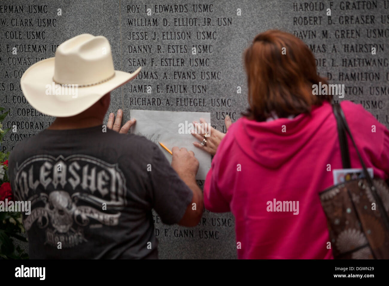 Jeff Hudson, left, and his spouse Debra Hudson, right, trace the name ...