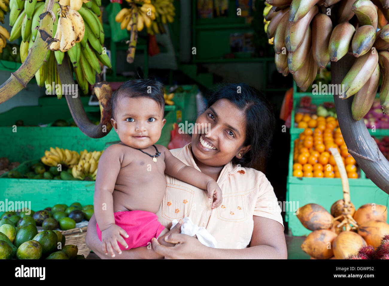 Female vendor holding her baby, market stall selling fruit and ...