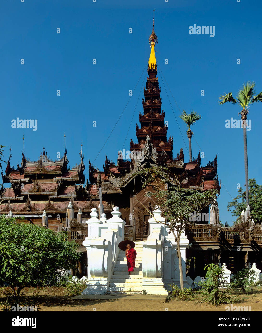 Monk on the stairs outside a building made of teak, Shwe In Bin Kyaung ...