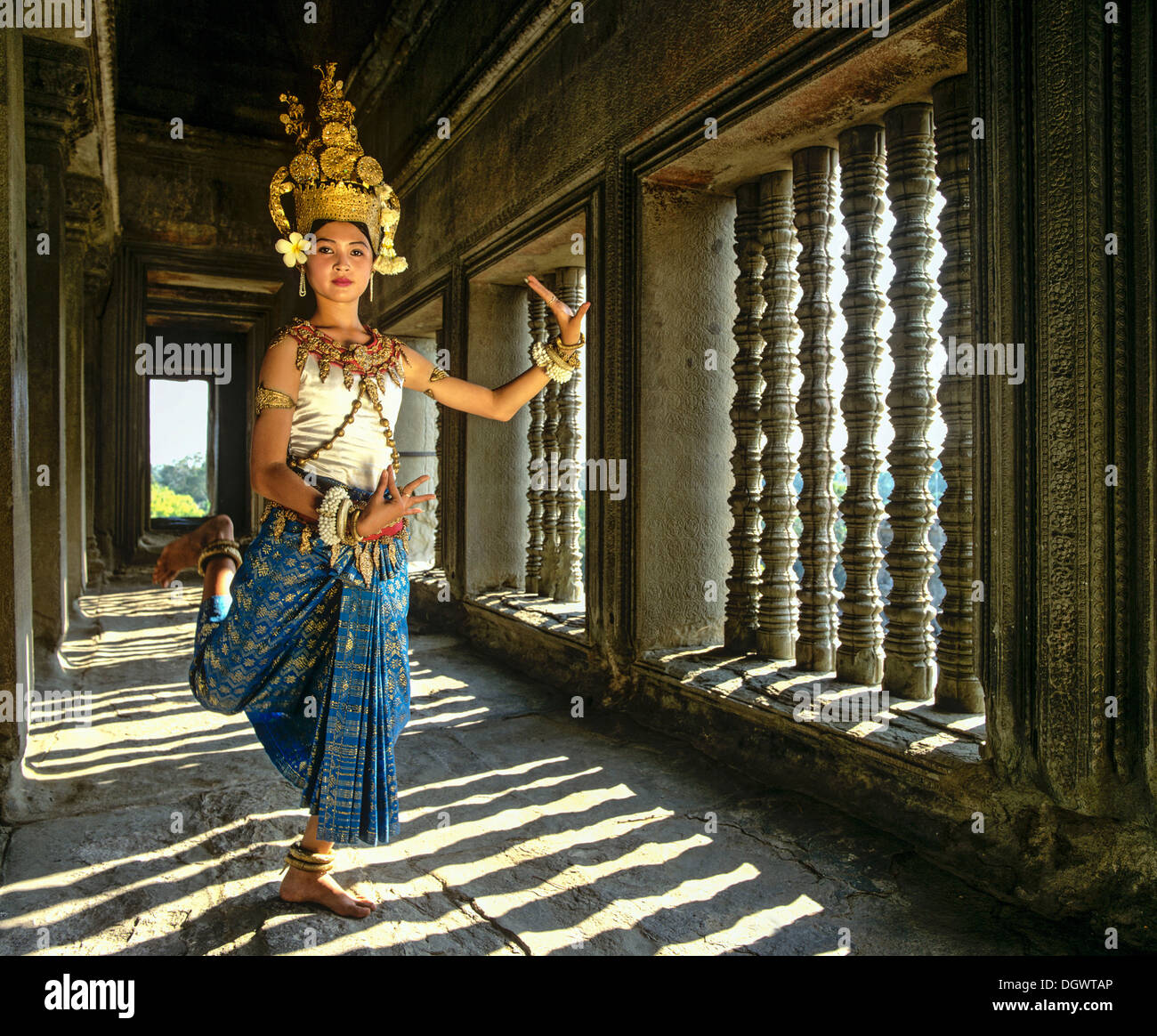 Temple dancer or apsara posing in front of the baluster windows in the ...