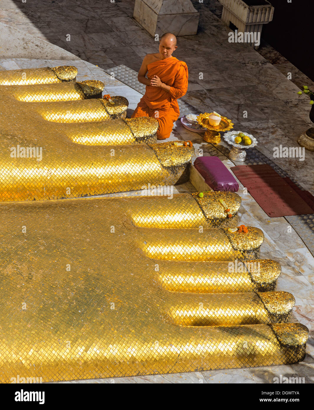 Monk praying at the feet of the golden Buddha statue of Wat ...