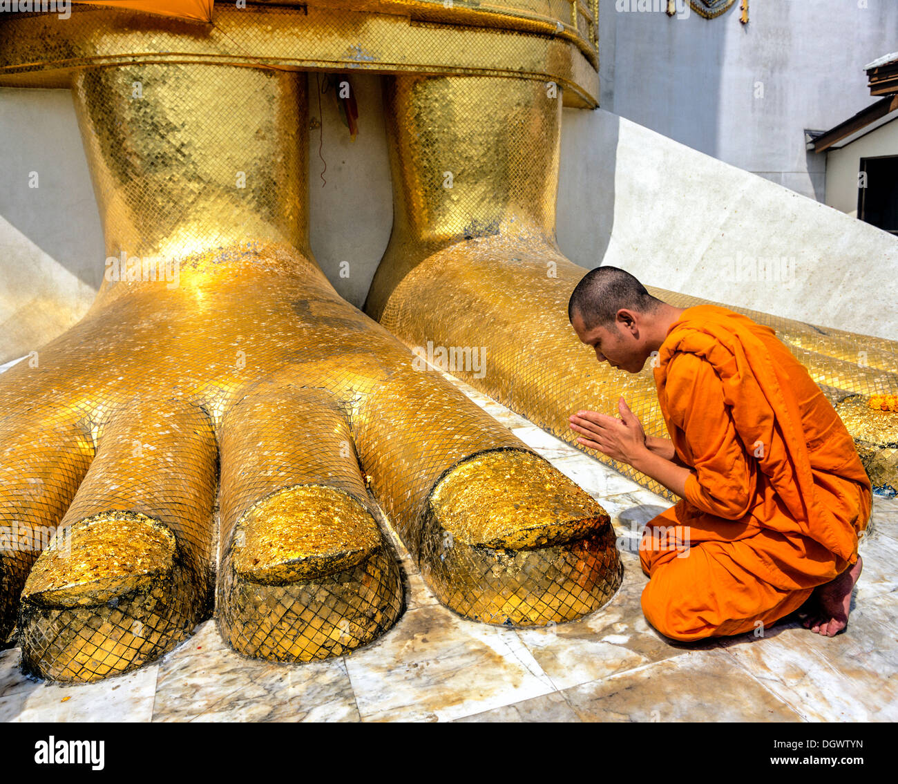 Monk praying at the feet of the golden Buddha statue of Wat ...