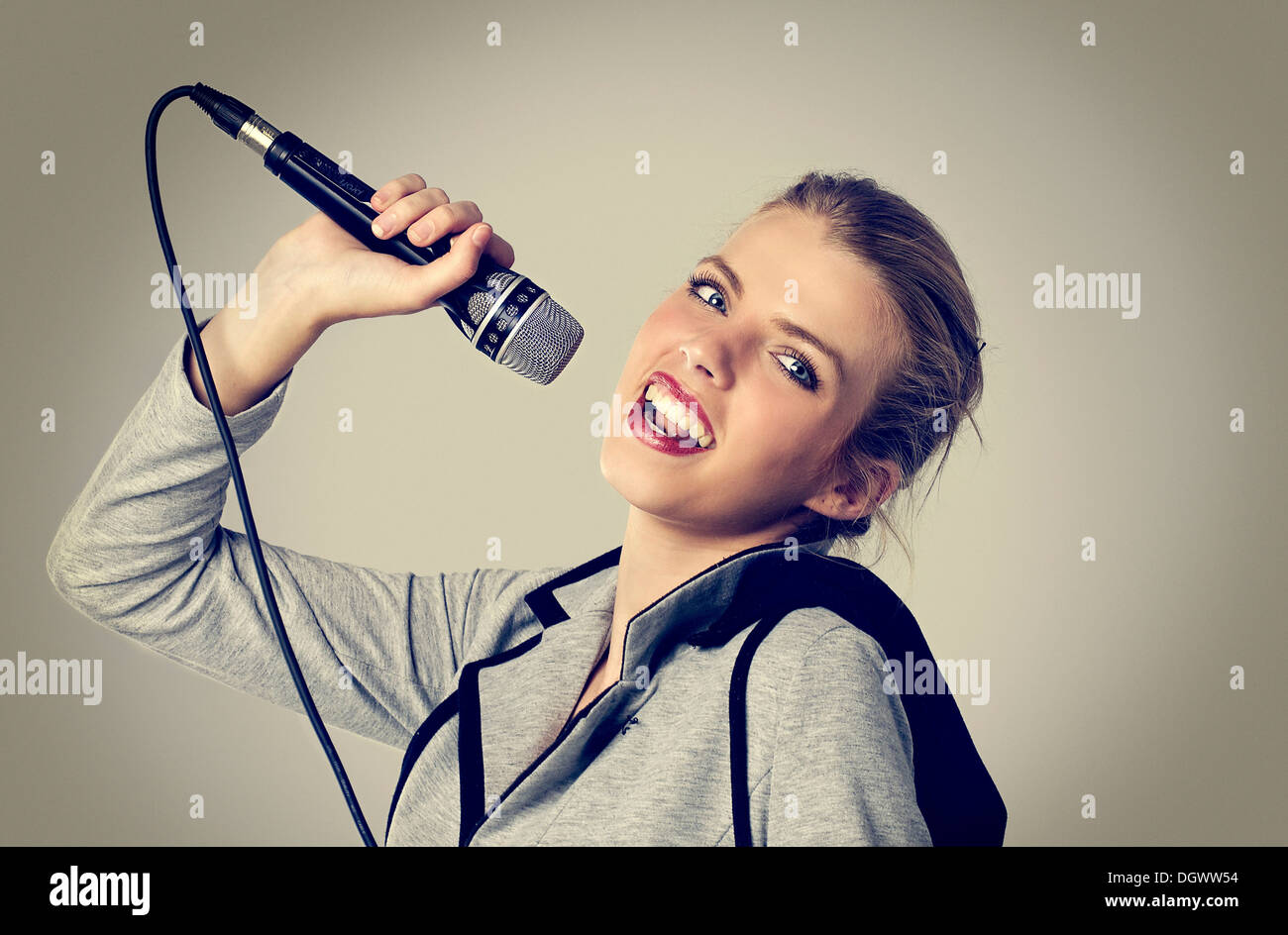 Young woman holding a microphone in a singer pose Stock Photo - Alamy
