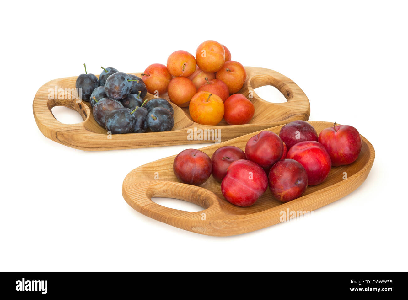 Different varieties of plums in wooden plates isolated on white ...