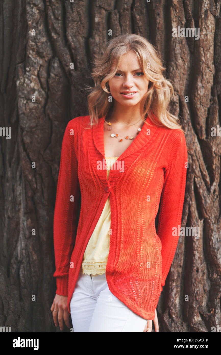 Beautiful blond woman posing on tree trunk background Stock Photo - Alamy