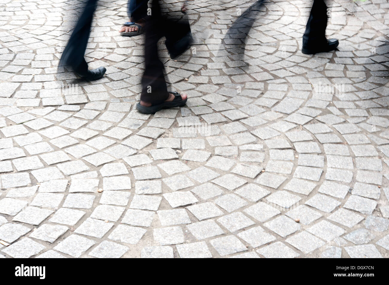 Movement of commuters feet (blurred), walking across cobbled pavement ...