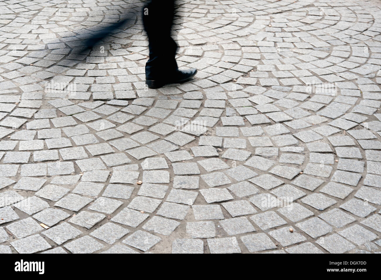 Movement of commuters feet (blurred), walking across cobbled pavement ...
