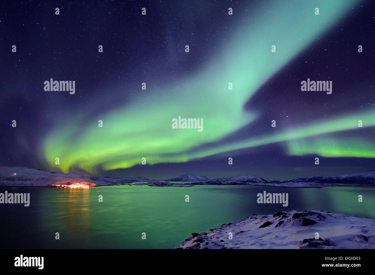 Aurora over a fjord with snow-covered mountains and an illuminated ...
